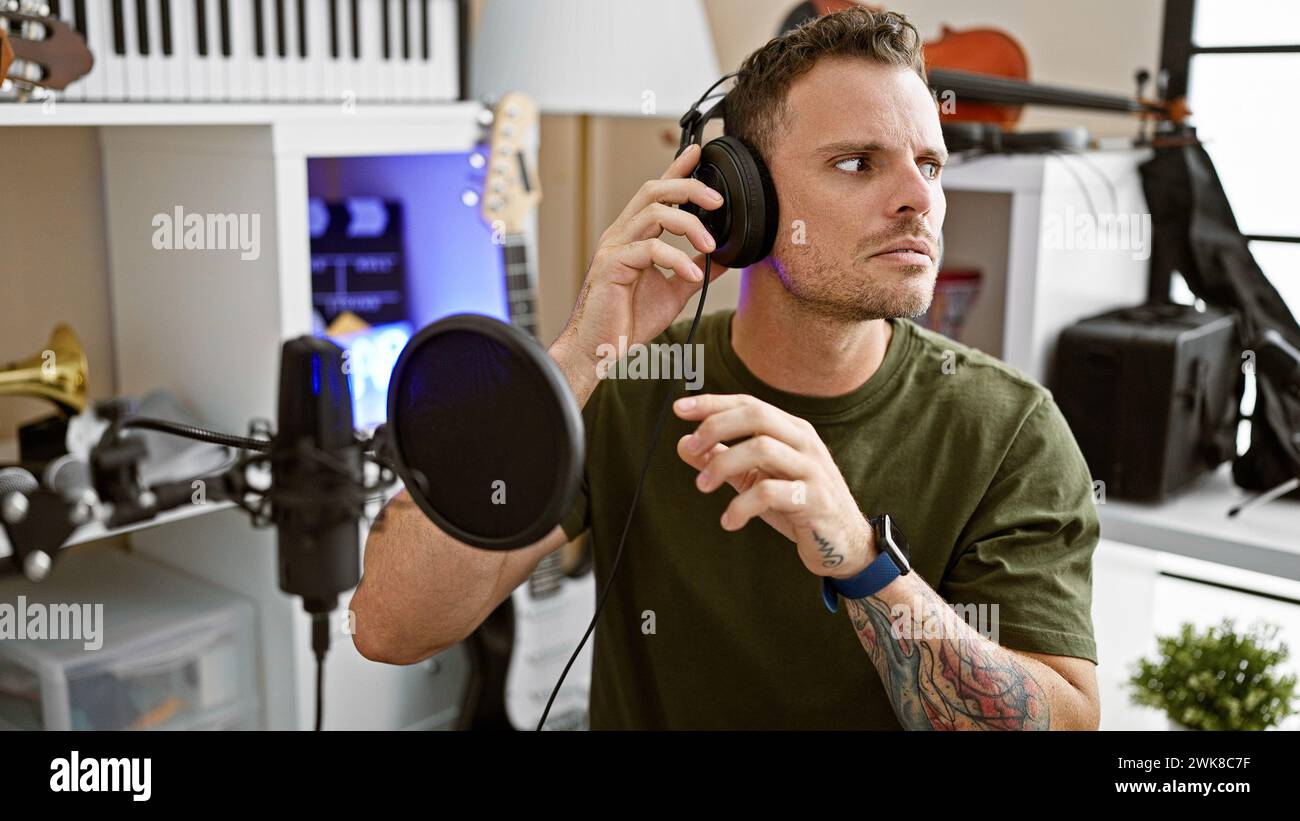 Focused man with headphones in music studio adjusting microphone for ...