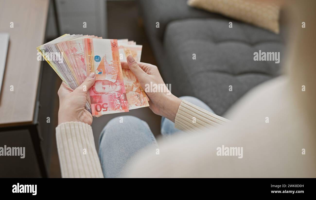 Young caucasian woman counting philippine pesos indoors, portraying an ...