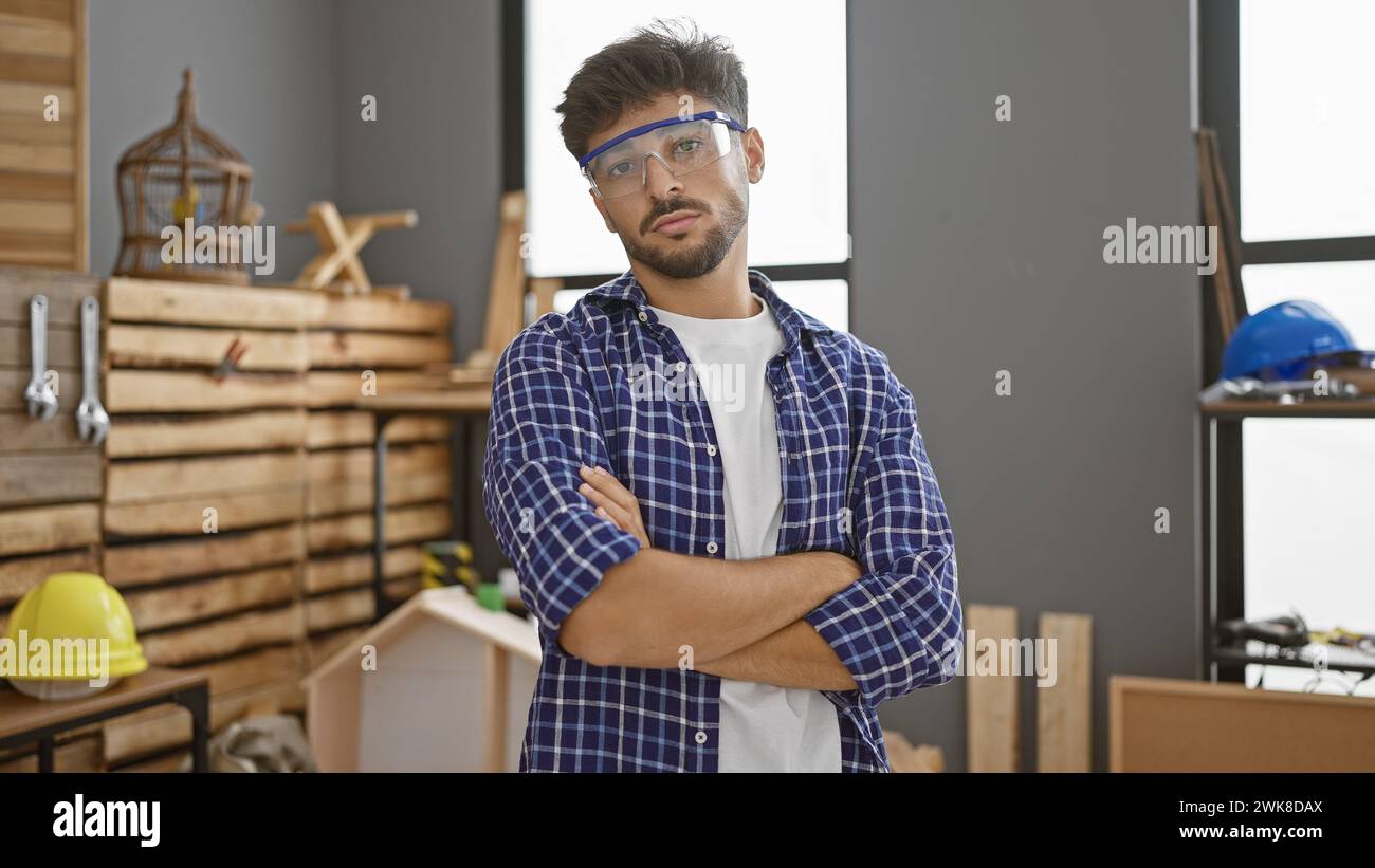 Serious-faced young arab carpenter with crossed arms standing ...