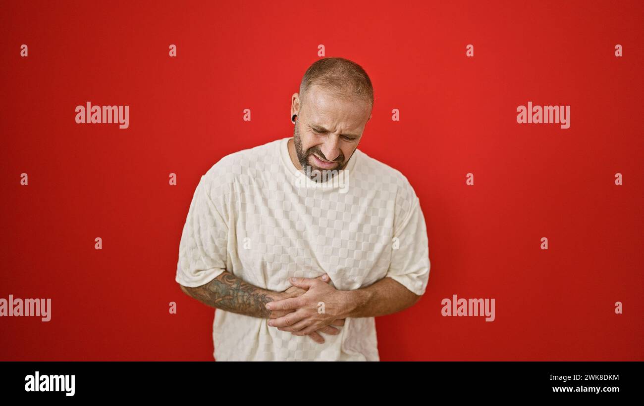 Worried young man, cool yet serious, suffering stomach ache ...