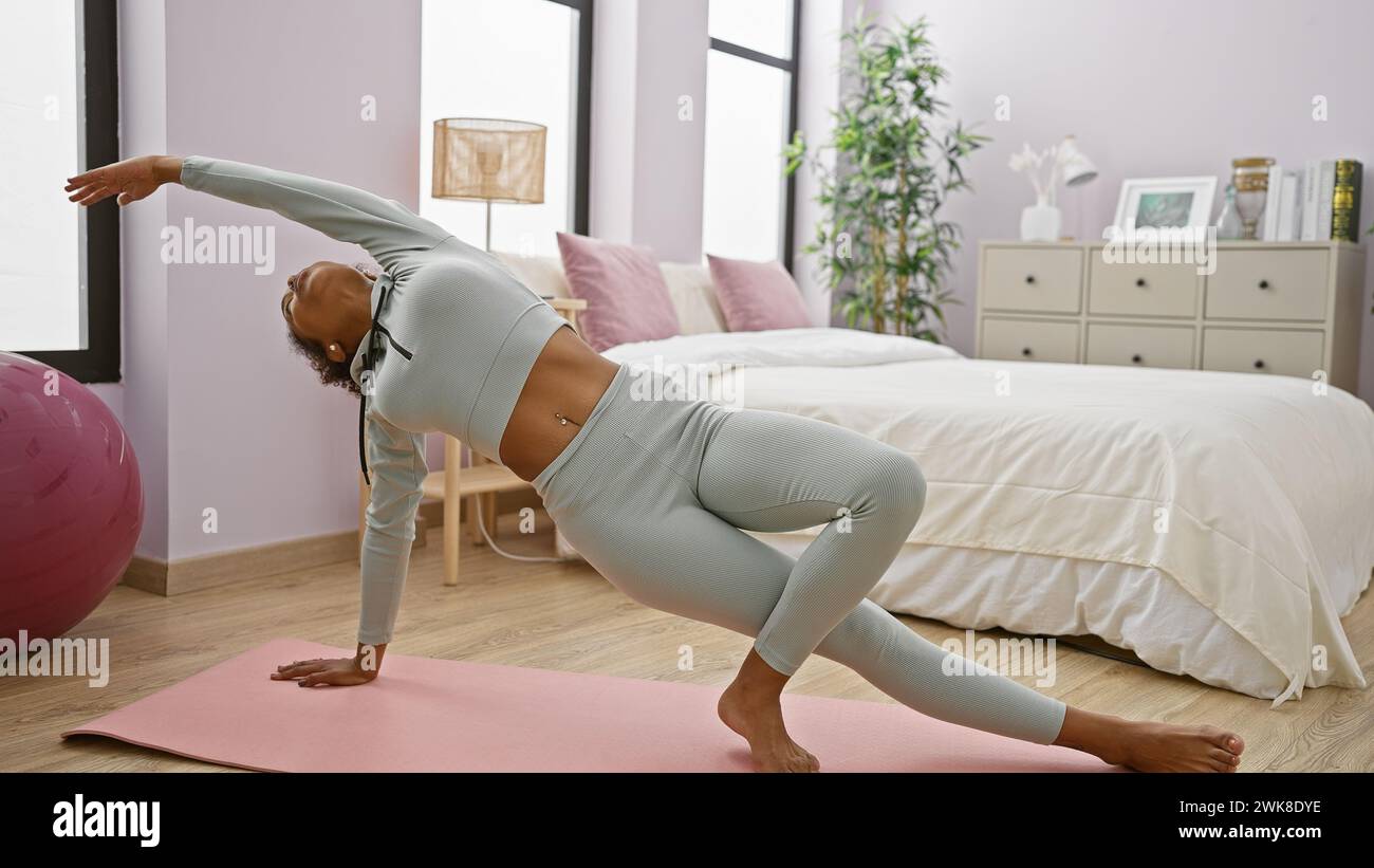 African american woman practicing yoga in a modern bedroom with a ...