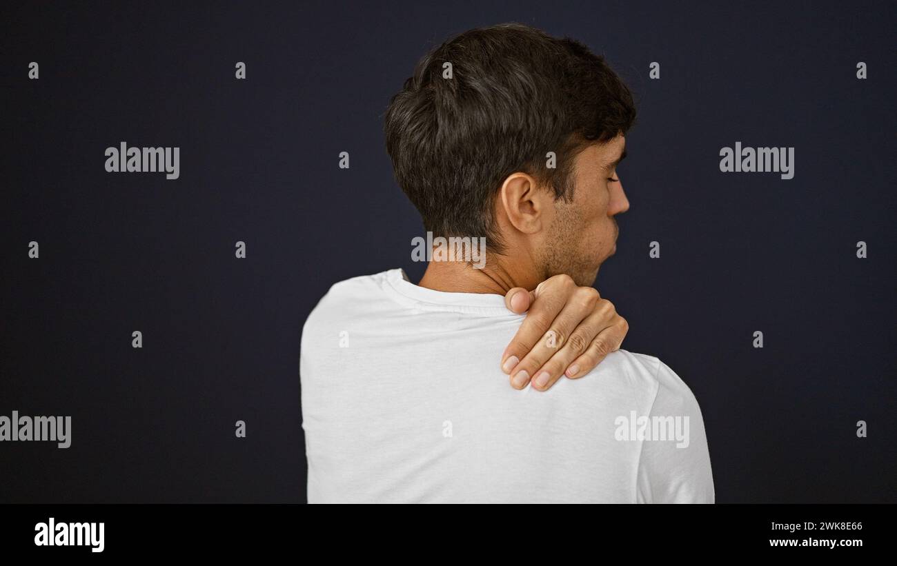 Distressed young hispanic man suffering intense back pain, isolated on ...