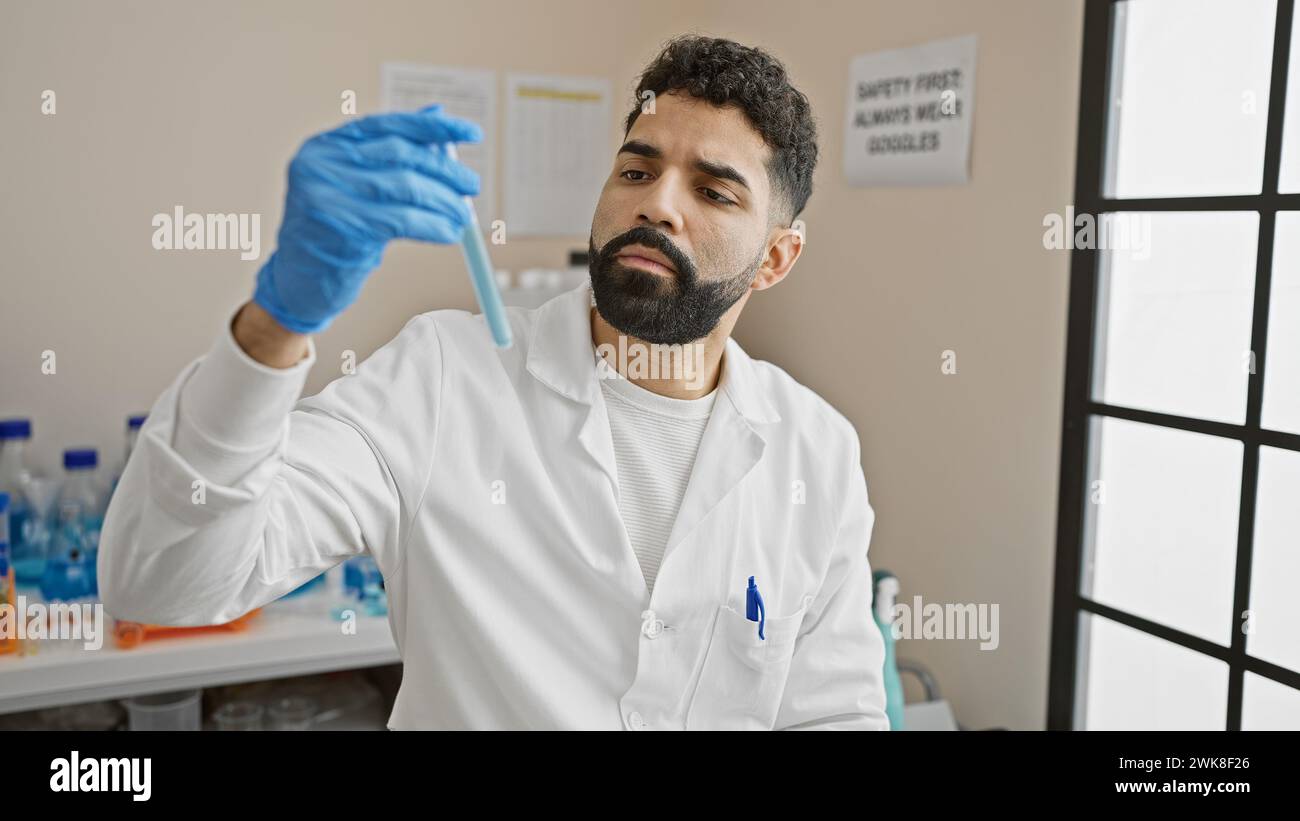 Hispanic man in lab coat examines a test tube indoors at a research ...