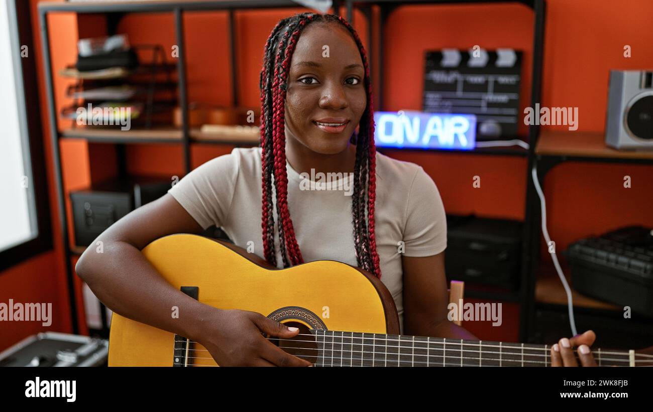 Smiling african american woman plays a classic melody on her guitar ...