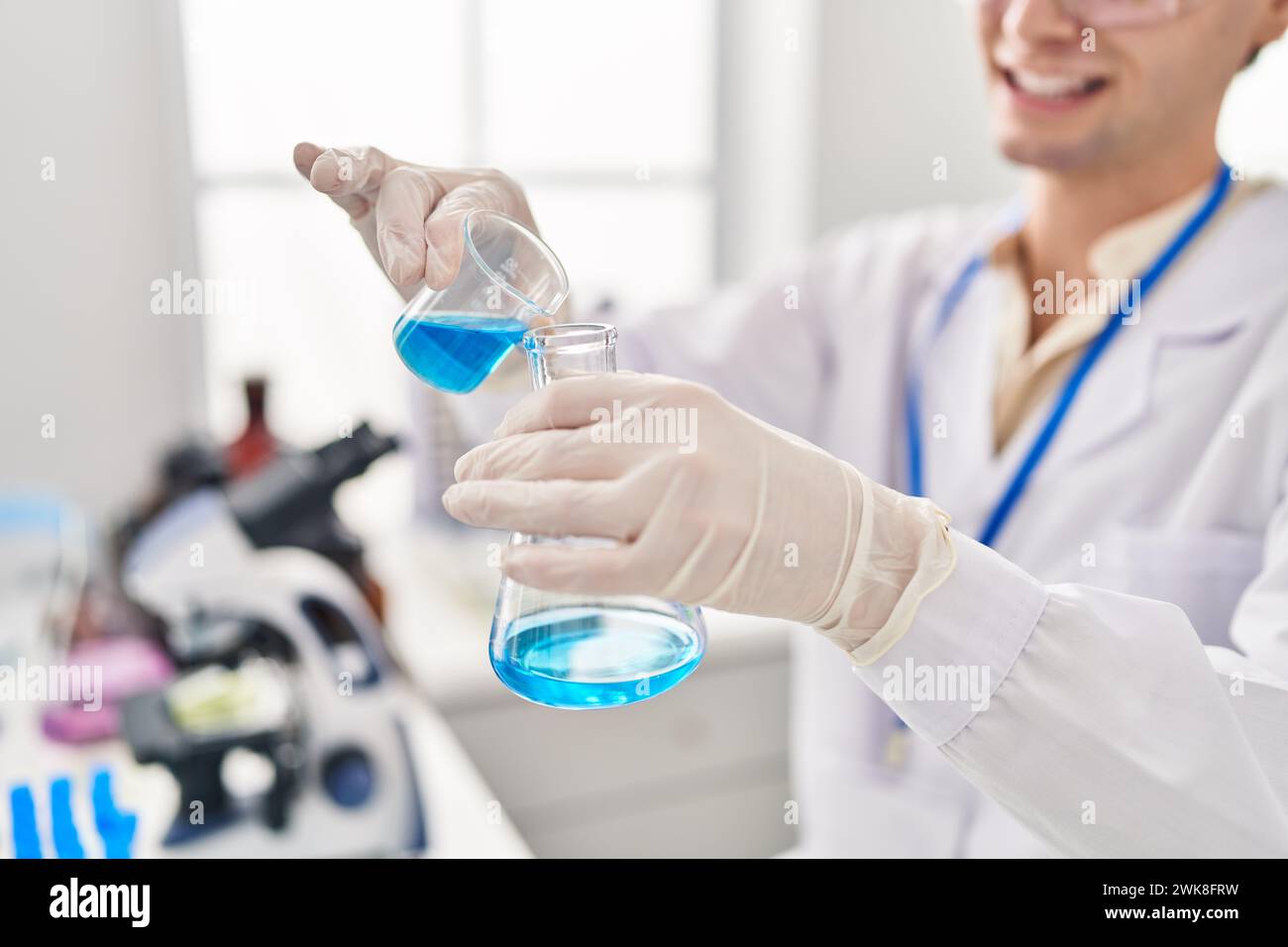 Young caucasian man scientist pouring liquid on test tube at laboratory ...
