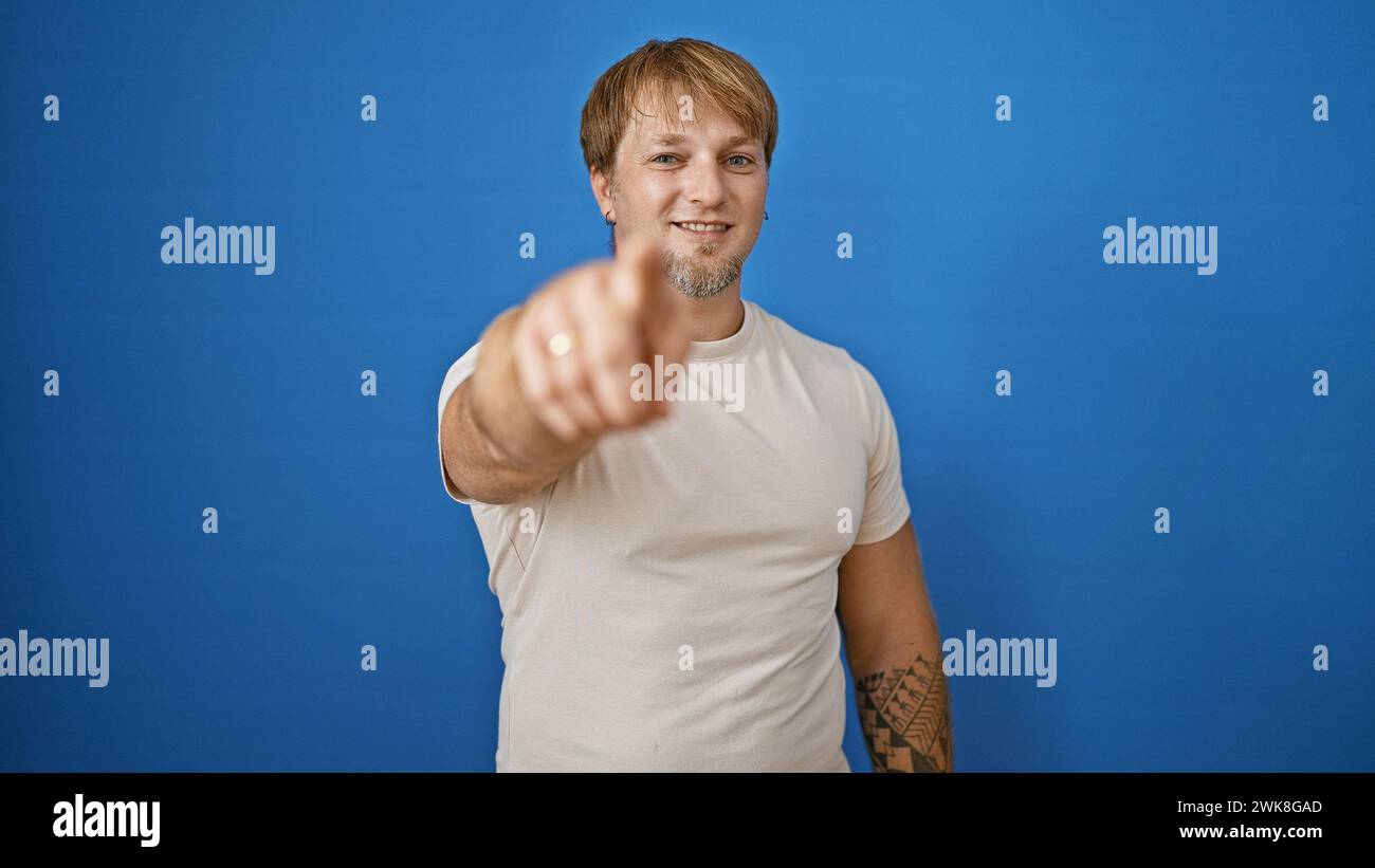Handsome bearded caucasian man pointing at camera against a vivid blue ...