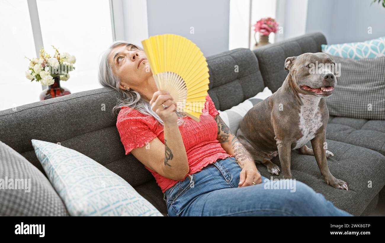 In the heat at home, a mature middle age, grey-haired woman sitting ...