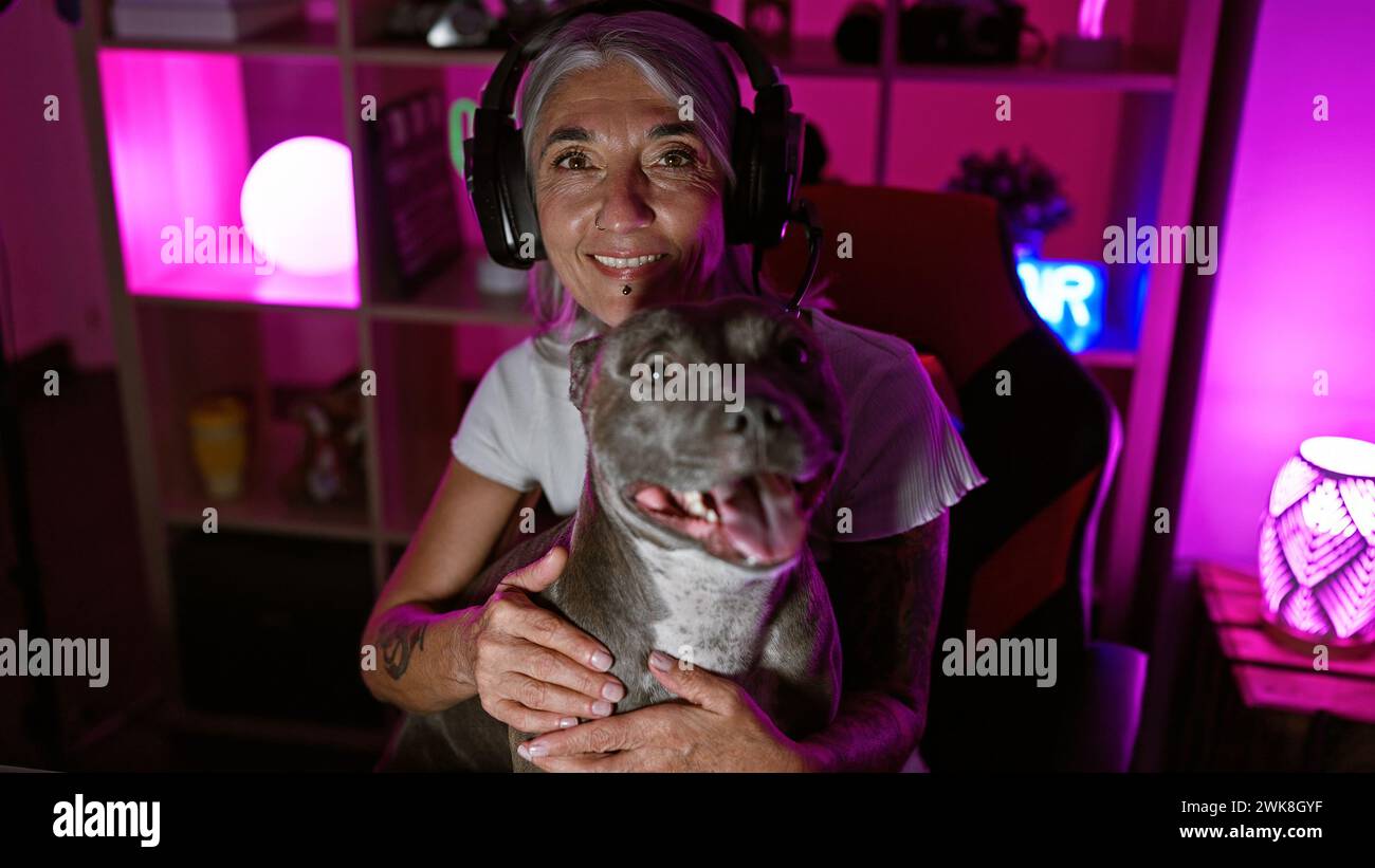 Smiling middle-aged grey-haired woman streamer, rocking headphones and ...