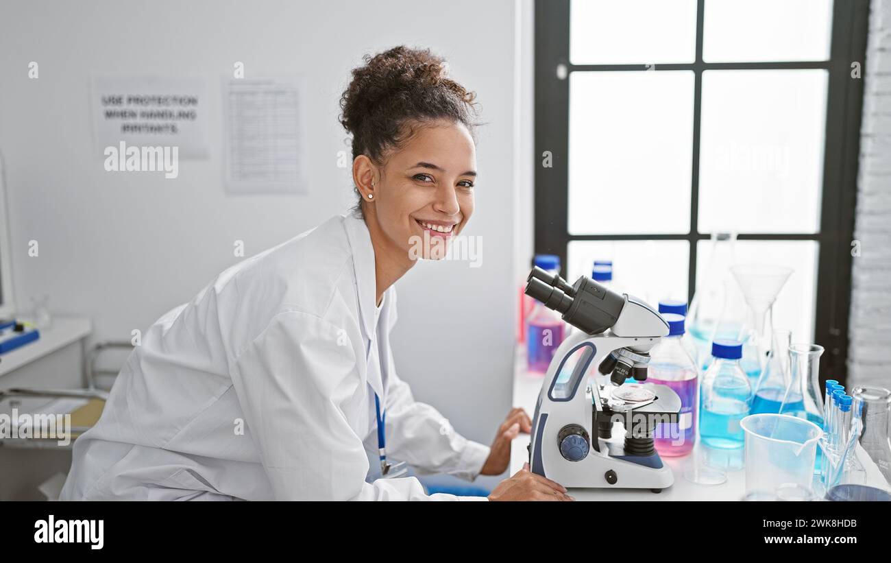 Confident and beautiful young hispanic woman scientist, sporting curly hair, enjoys performing ...