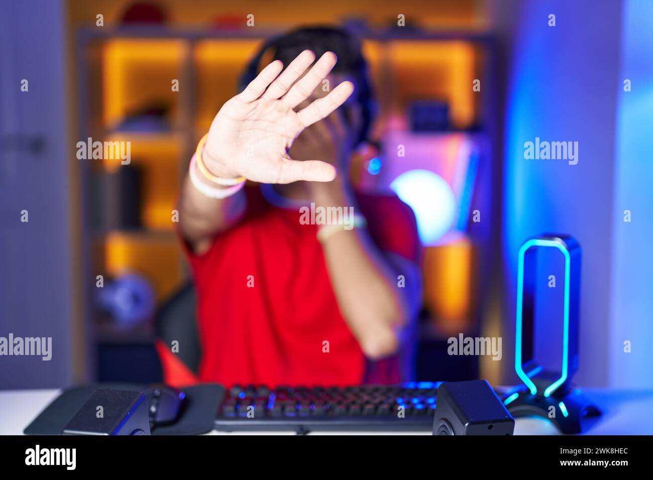 Young hispanic man playing video games covering eyes with hands and ...