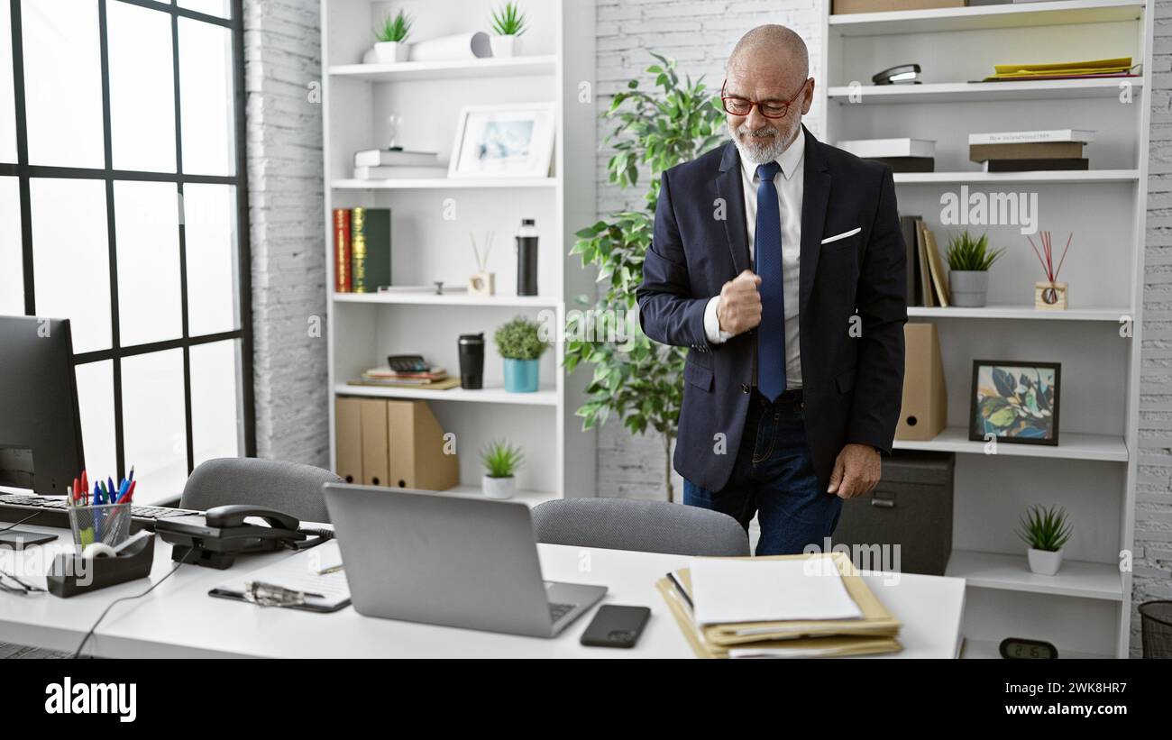 Confident mature man with a beard in a modern office adjusting his suit ...