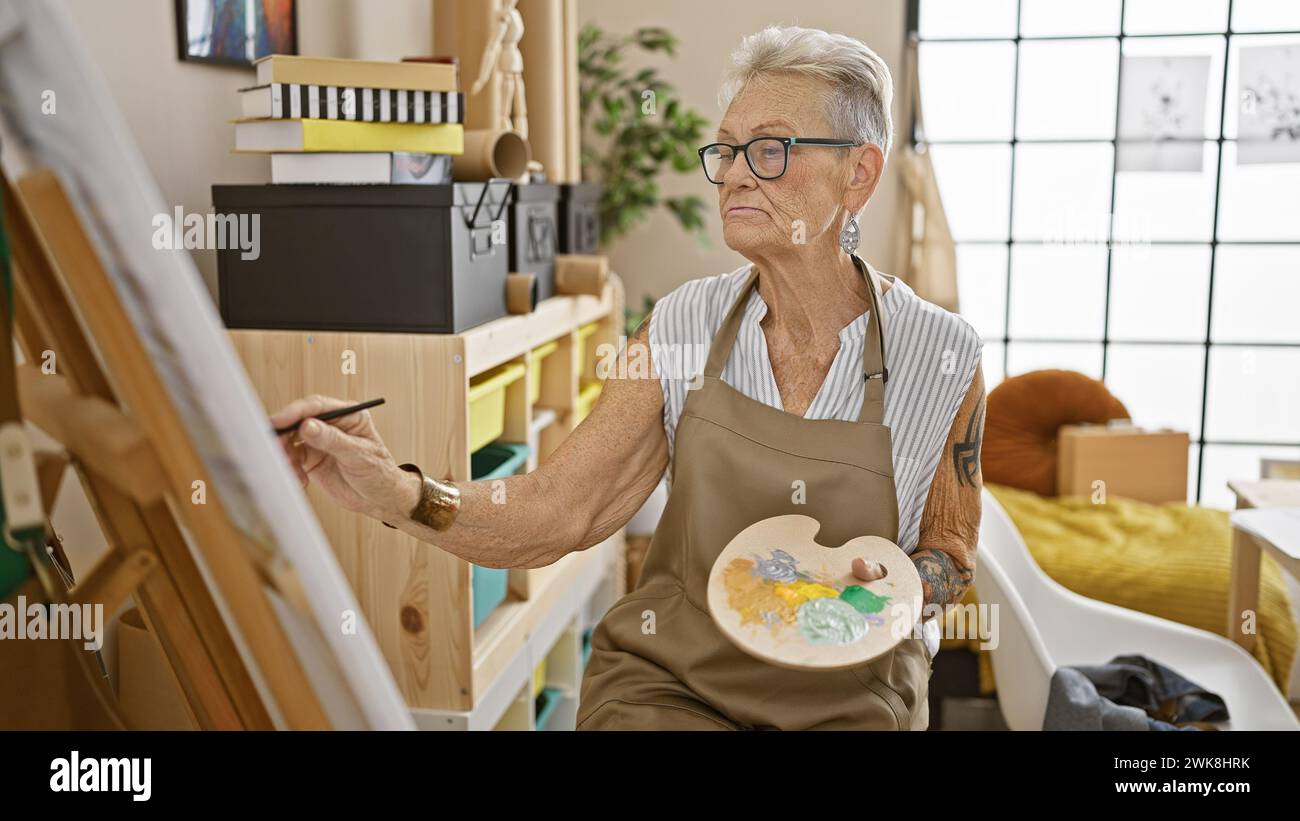 Mature, grey-haired female artist fully immersed in her art, diligently ...