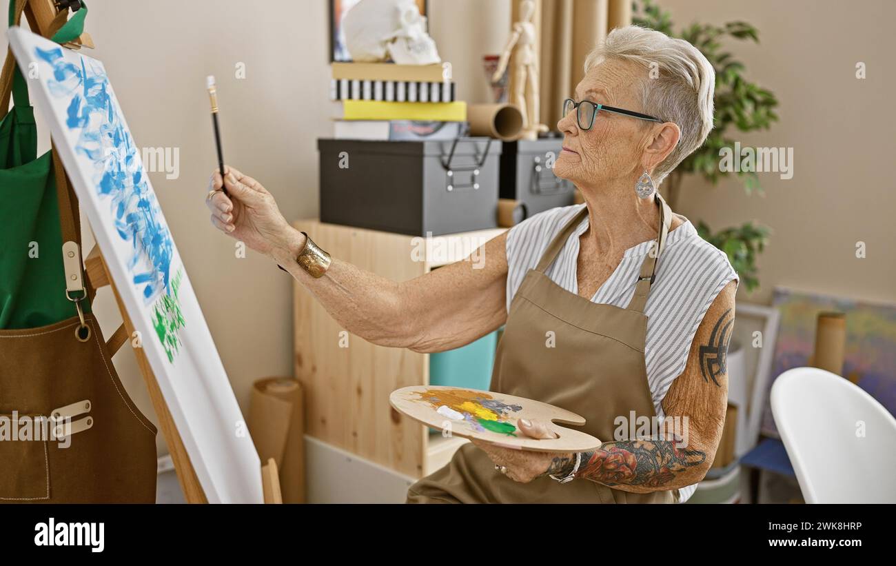 Mature, grey-haired female artist fully immersed in her art, diligently ...