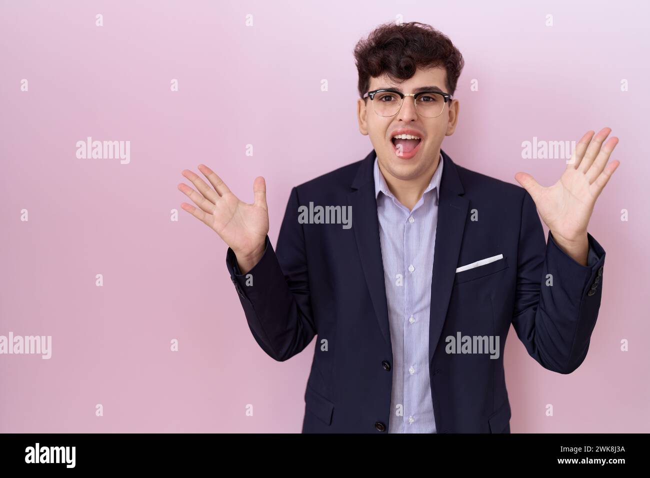 Young non binary man with beard wearing suit and tie celebrating crazy ...