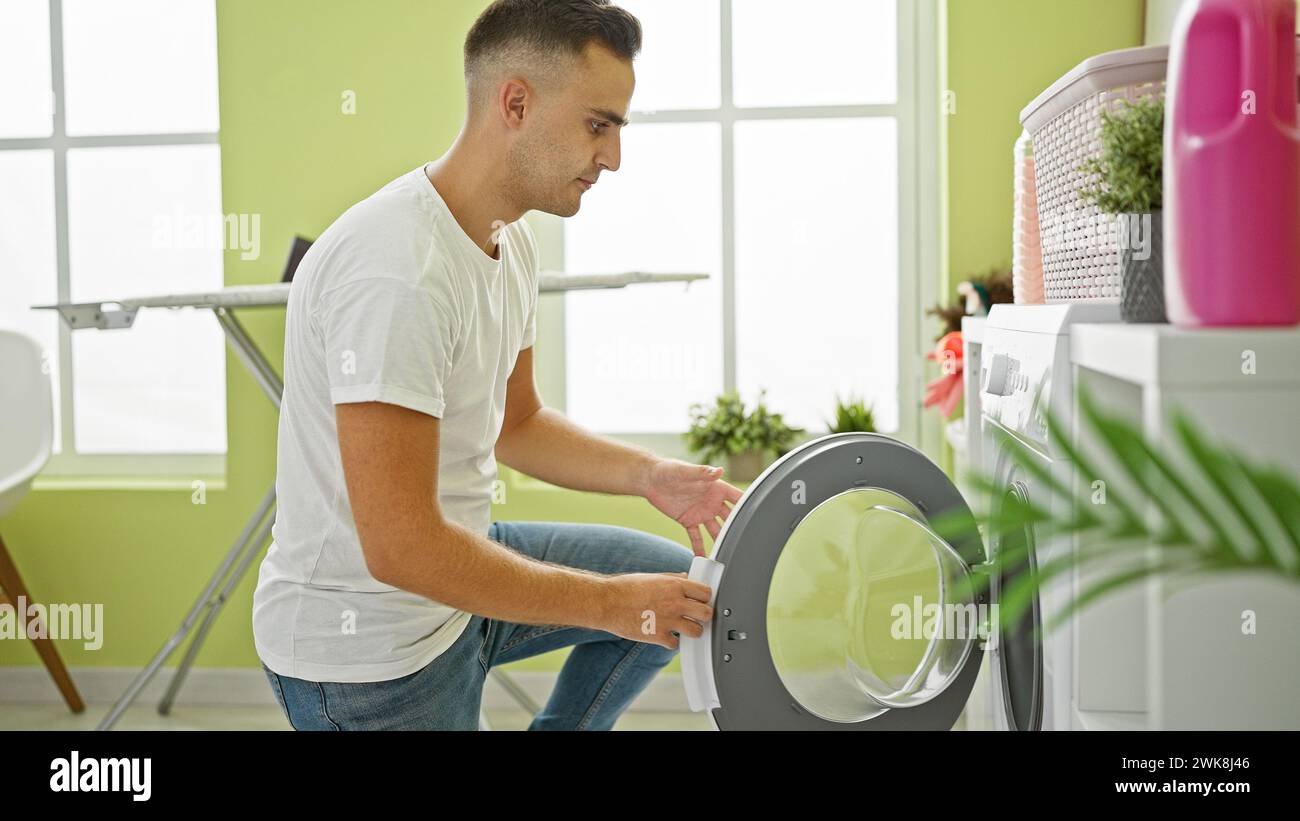 Handsome young man doing laundry in a bright room with green wall Stock ...