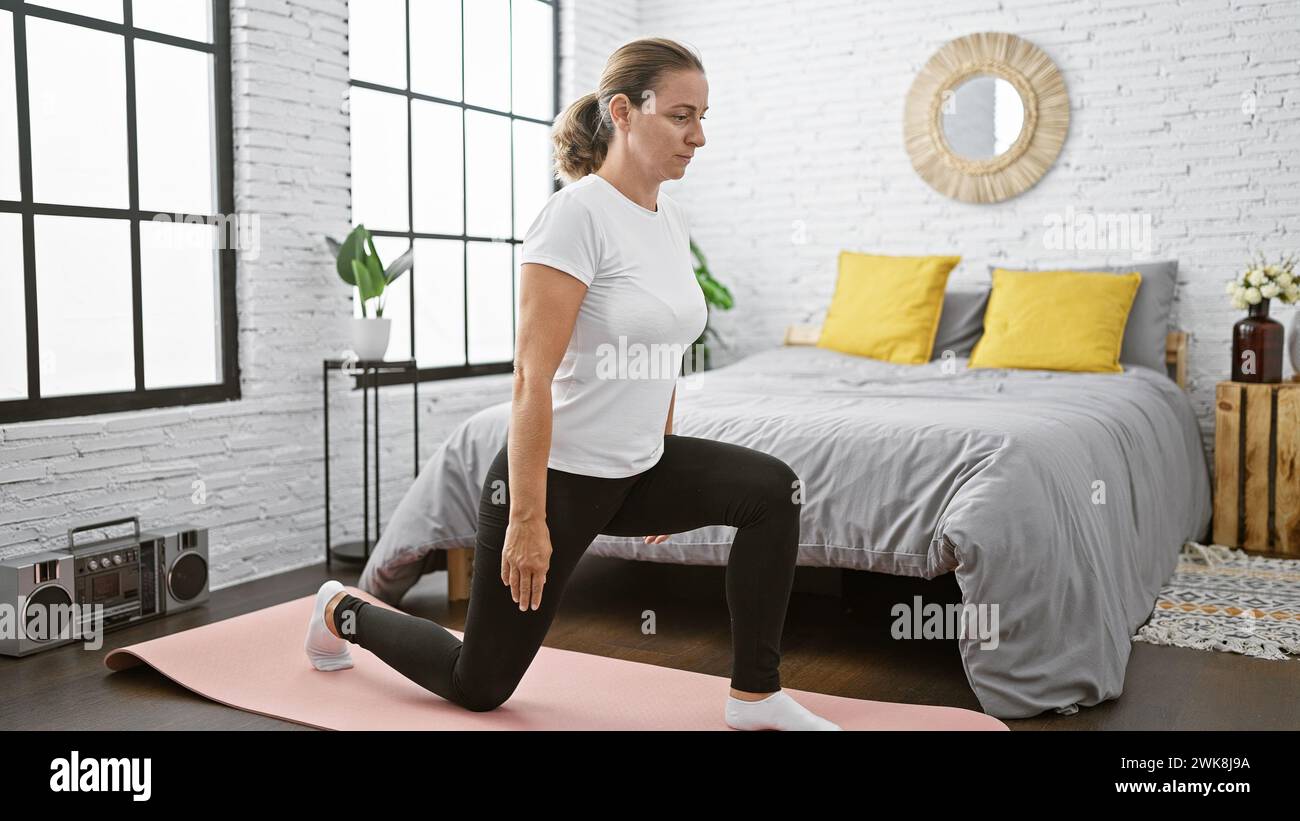 Awake & stretching, beautiful young blonde woman meditating, posing in ...