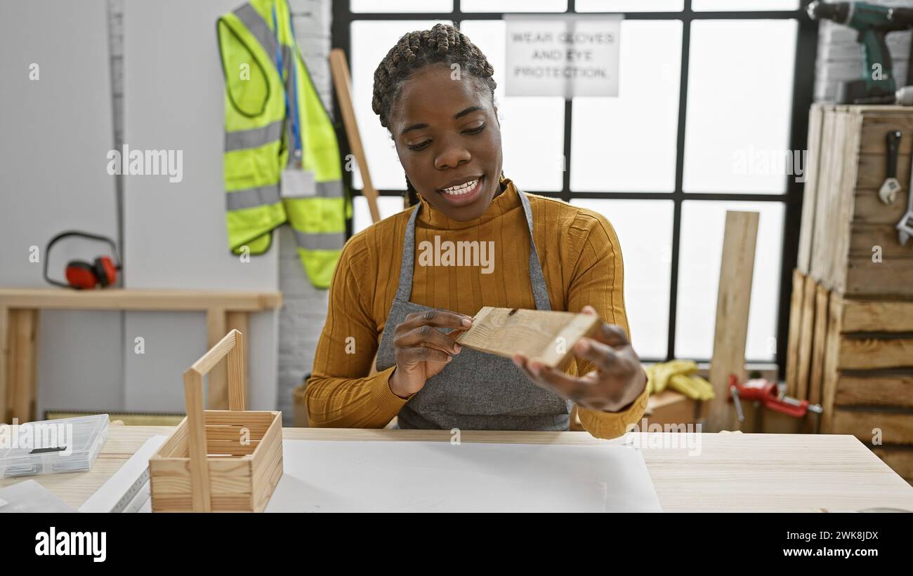 African american woman with braids examines wood in a workshop ...