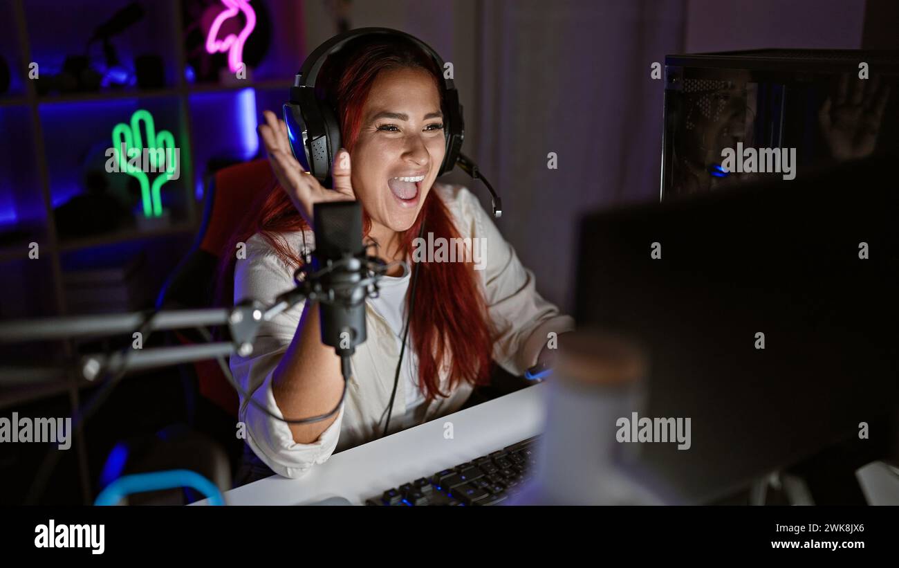 Smiling young redhead woman streamer engaging in a lively video call ...