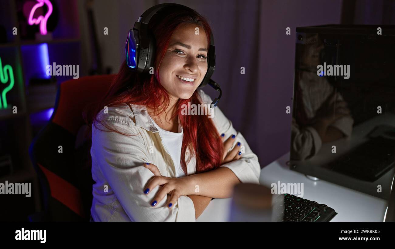 Relaxed young redhead woman streamer, arms crossed, flashes a smile ...