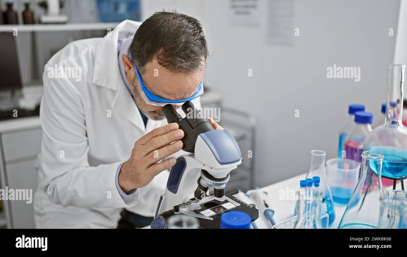 Mature man with grey hair- a scientist captured at work in a laboratory ...