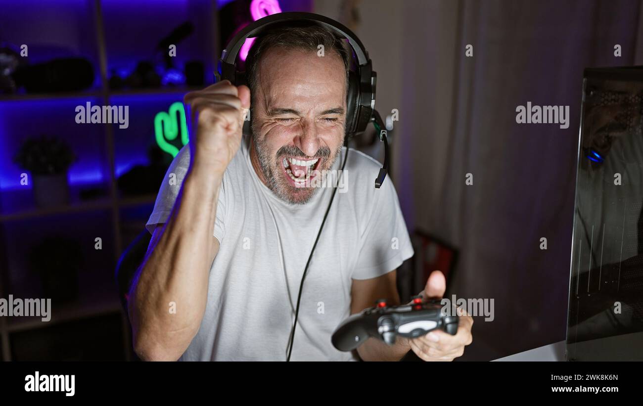 Middle age grey-haired male streamer joyfully celebrates his game win ...