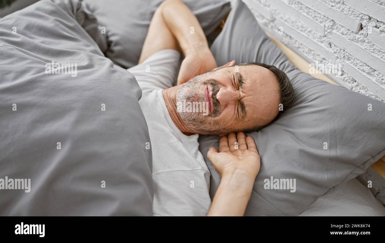 Exhausted, middle age man with grey hair, comfortably resting in the cozy comfort of his bedroom ...