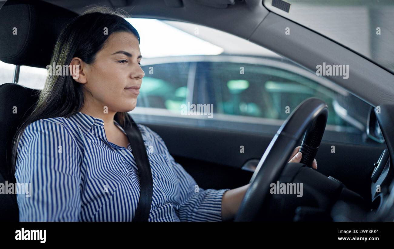 Young beautiful hispanic woman driving a car at parking lot Stock Photo ...