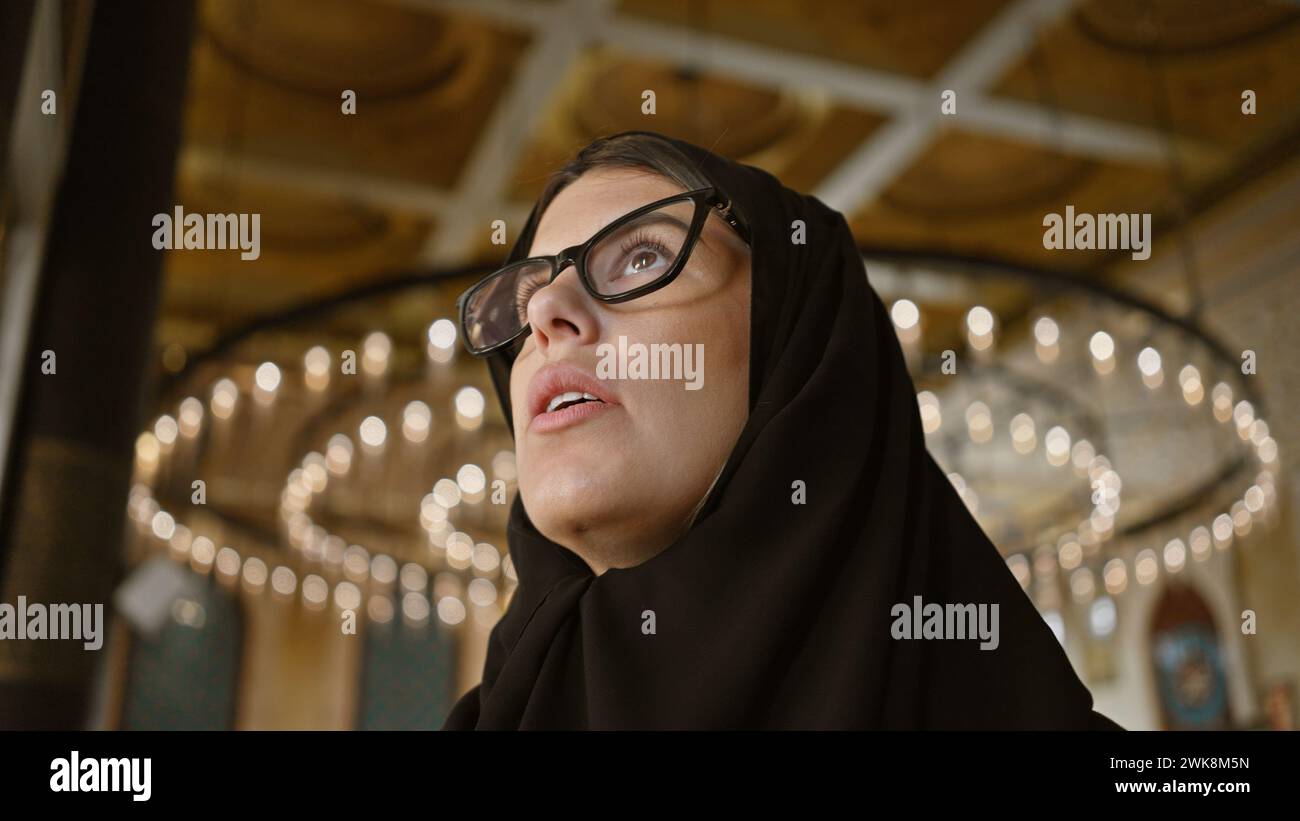 Young adult hispanic woman wearing glasses and hijab inside a mosque ...