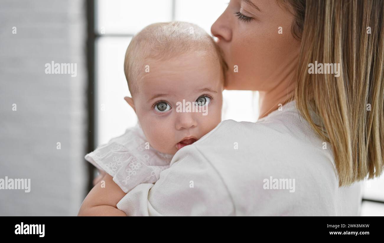 Casual and relaxed, a mother is standing, lovingly holding her baby ...