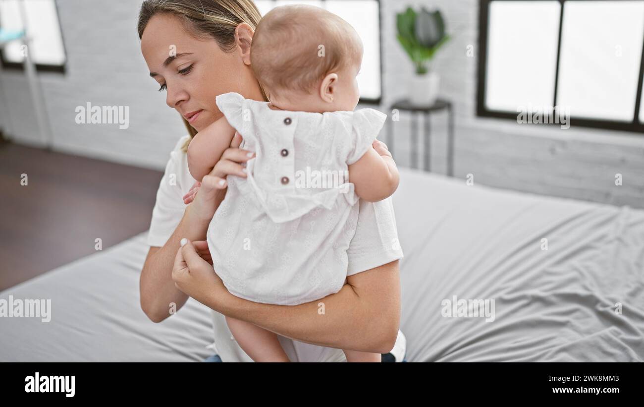 Confident mother enjoying fun moments, sitting on bed, trying to ...