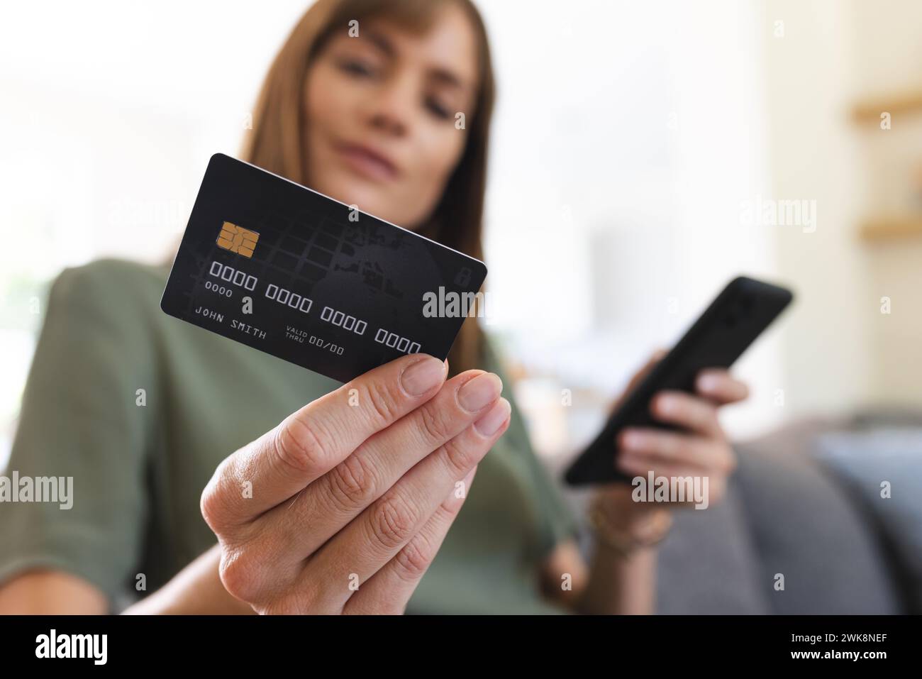 Woman manages finances online with card and phone, possibly paying or ...