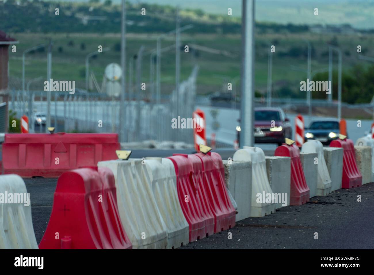 Red, white plastic safety barriers along road. Ensuring road safety ... Red, white plastic safety barriers along road. Ensuring road safety ...