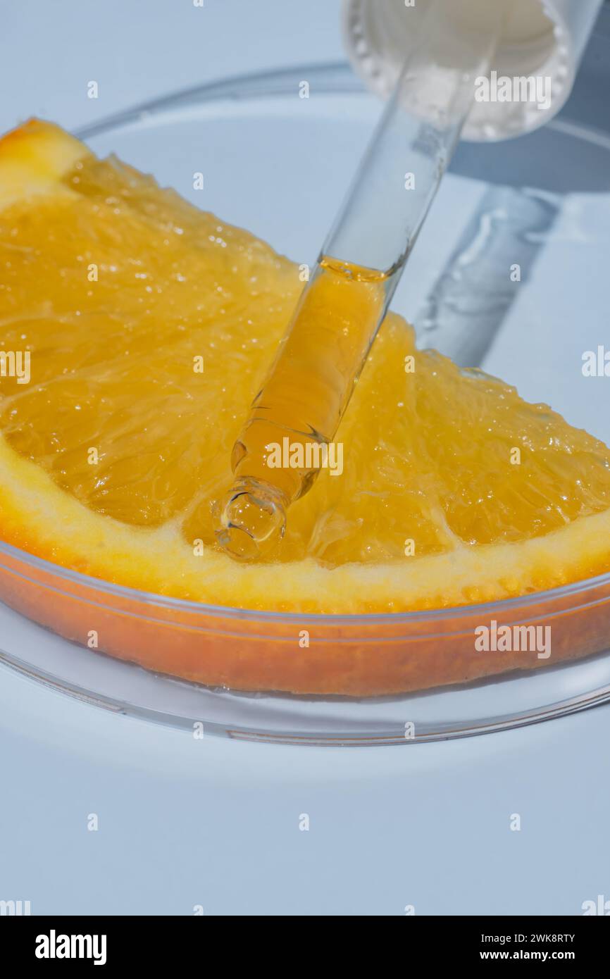 Glass pipette of AHA acid on an orange in glass circle petri dish, blue ...