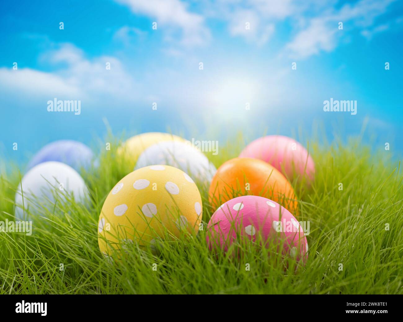 Colorful Easter eggs in a meadow under a bright blue spring sky with ...