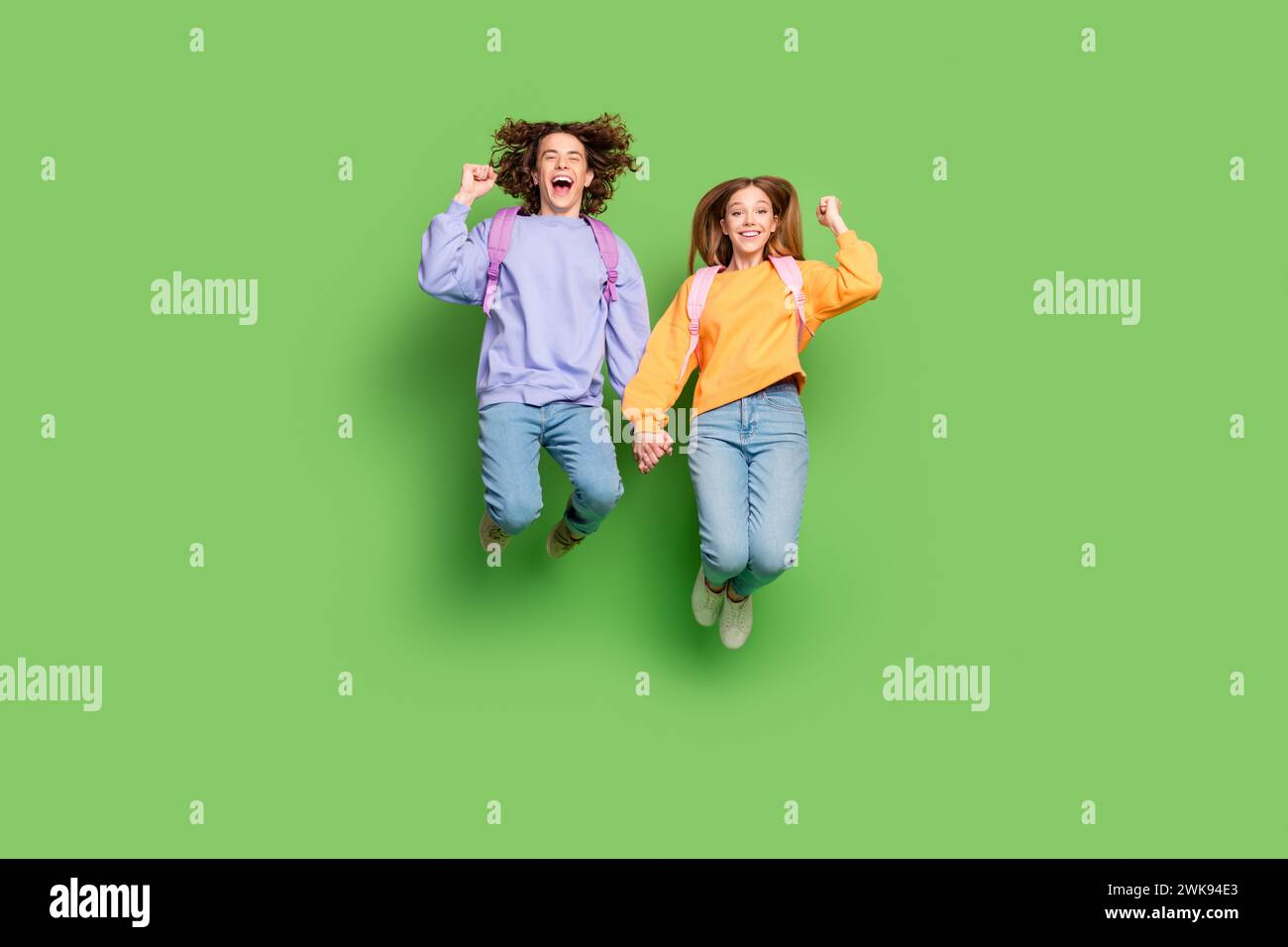 Full size portrait of two delighted people hold arms jump raise fists ...