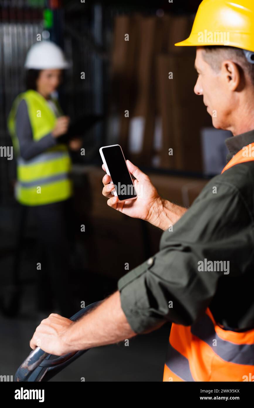 supervisor in safety vest and helmet using smartphone with employee in ...