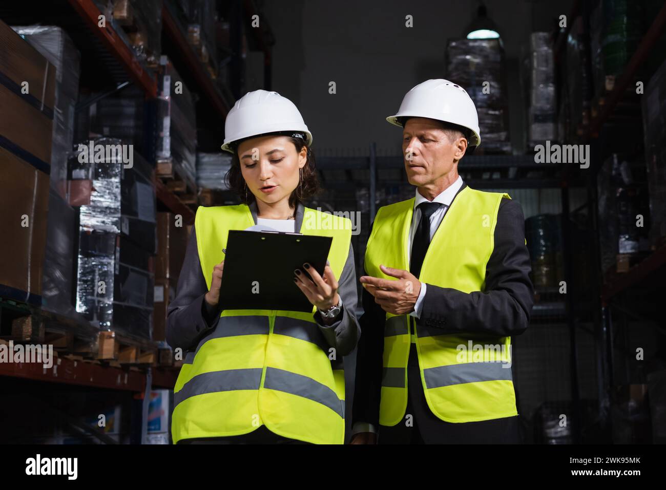 middle aged supervisor discussing work with female employee writing on ...