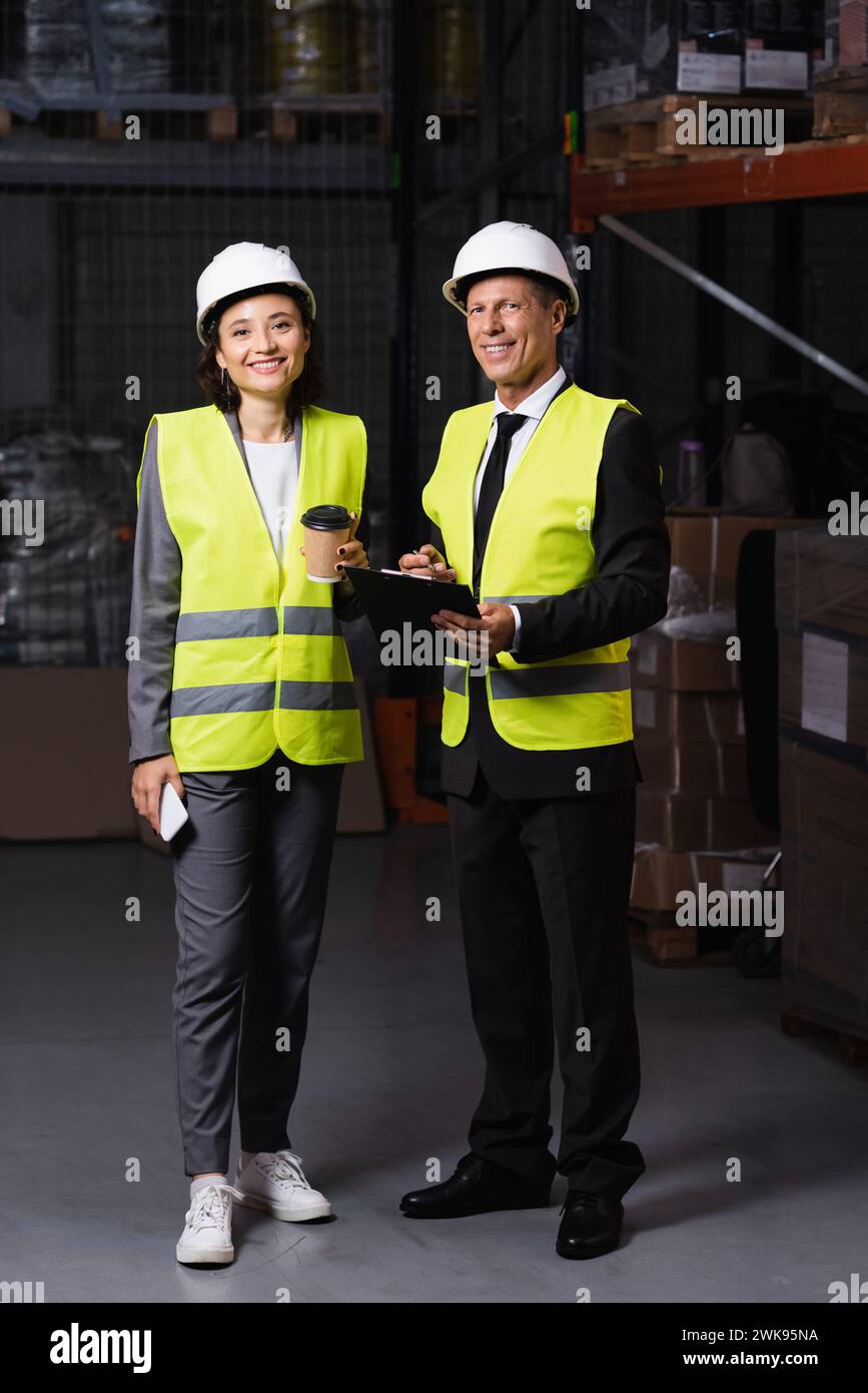 warehouse supervisor with clipboard and female employee with coffee and ...