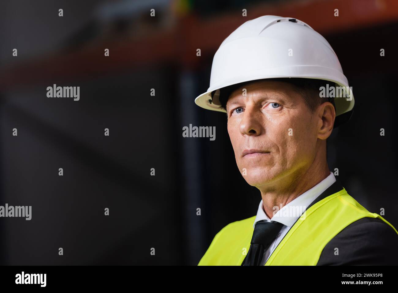 confident man in safety vest and hard hat looking at camera in ...