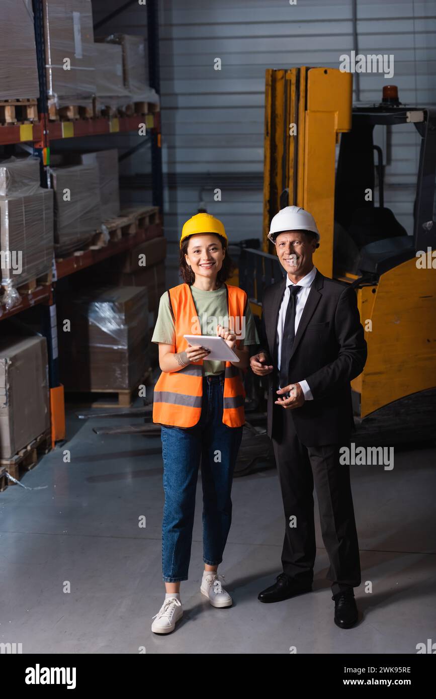 happy supervisor in suit and hard hat standing with female employee ...