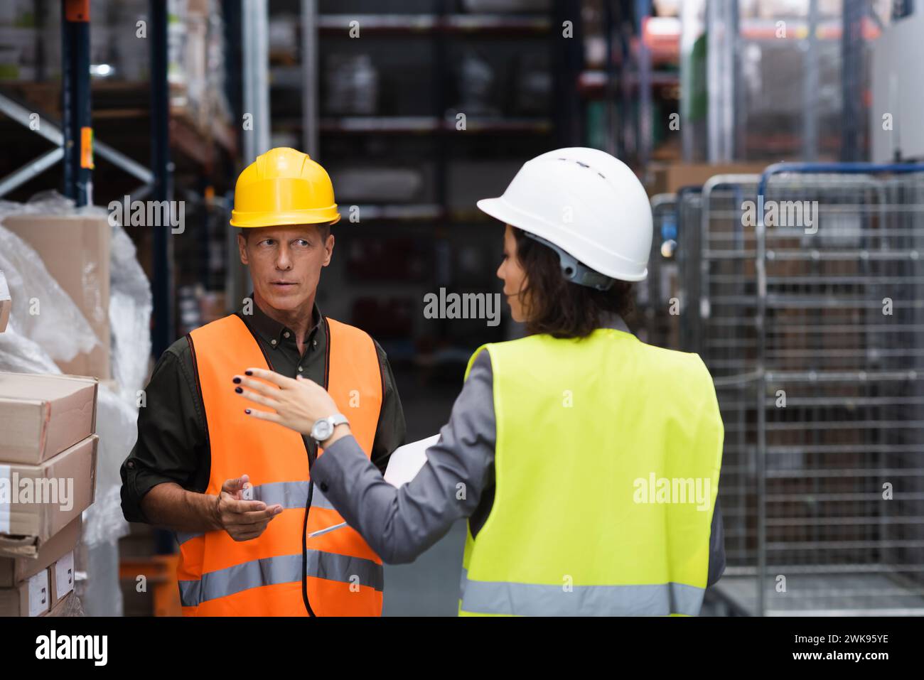 middle aged supervisor in hard hat having conversation with his female ...