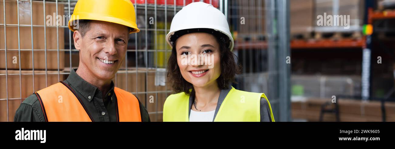 happy supervisor and employee in hard hats and safety vests looking at ...
