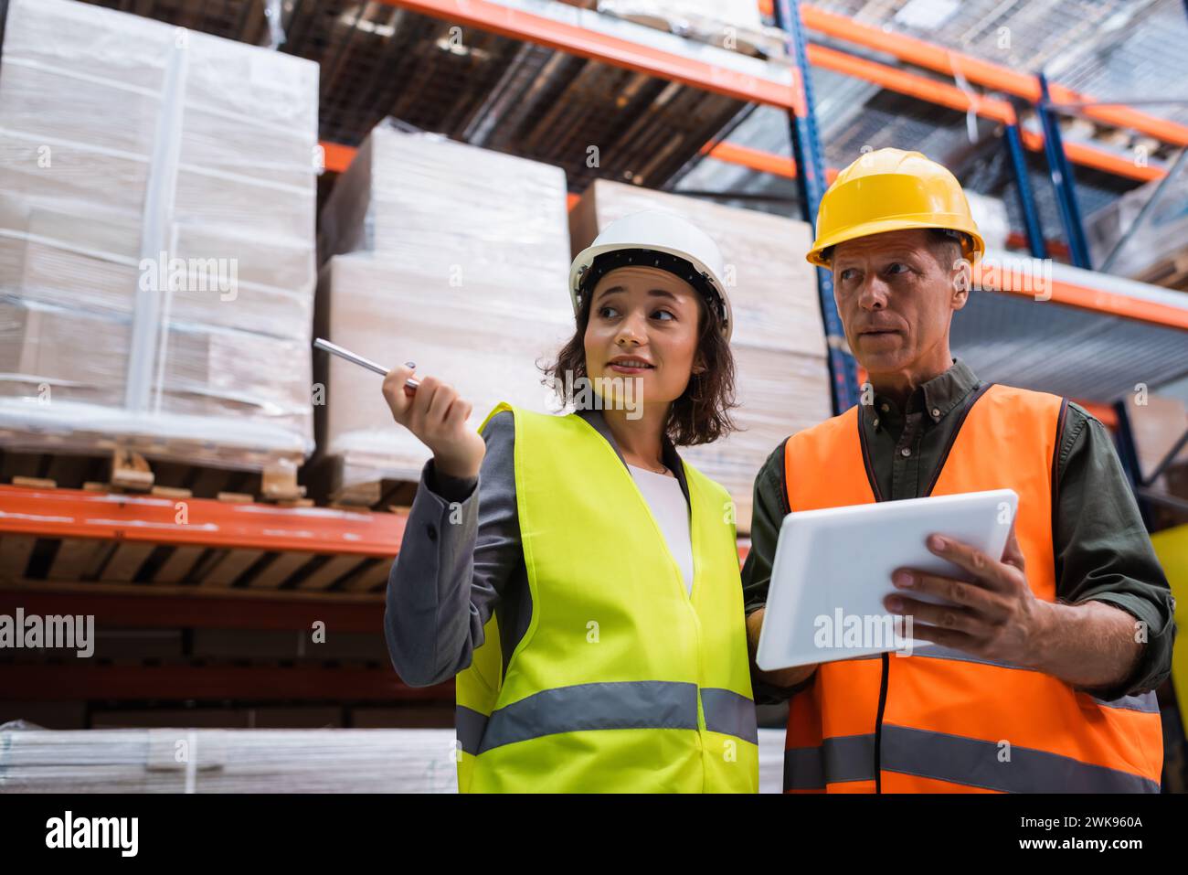 supervisor in hard hat holding tablet while discussing work to happy ...