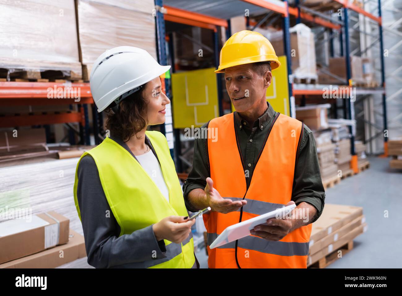 supervisor in hard hat holding tablet while discussing work to happy ...