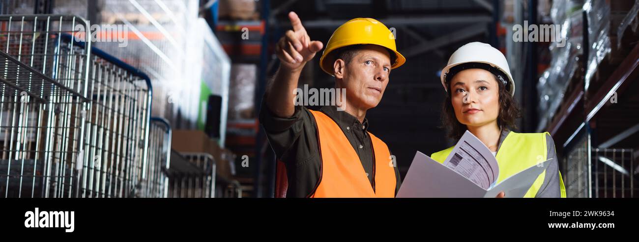 Two warehouse workers discussing logistics, middle aged man pointing ...