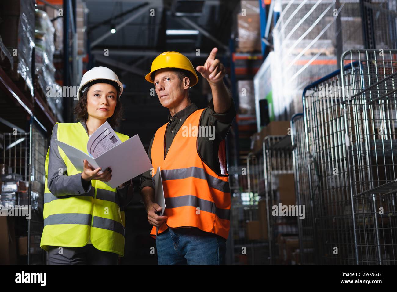 Two warehouse workers discussing logistics, middle aged man pointing ...