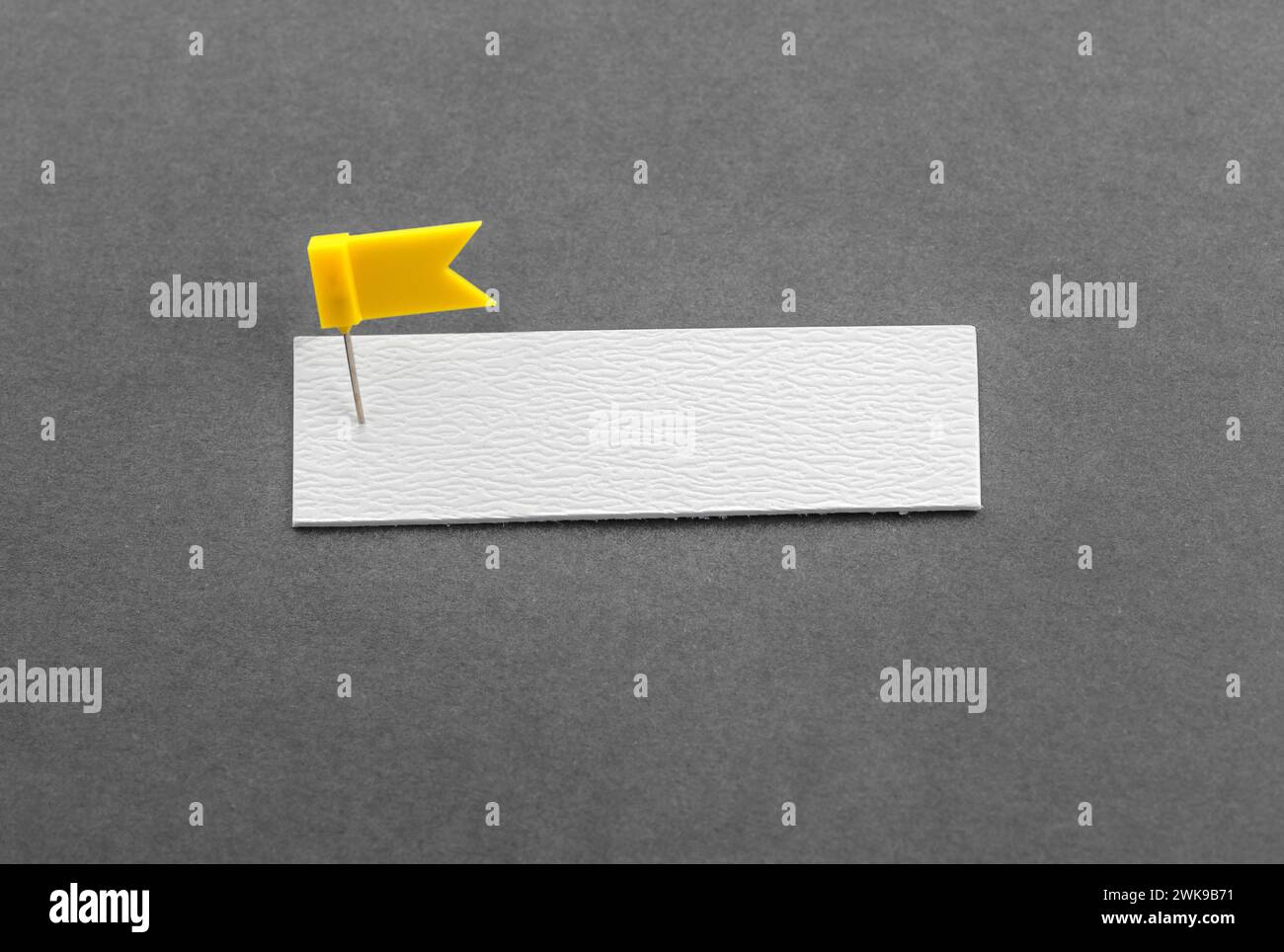 Blank note and yellow thumbtack on a gray background with copy space ...