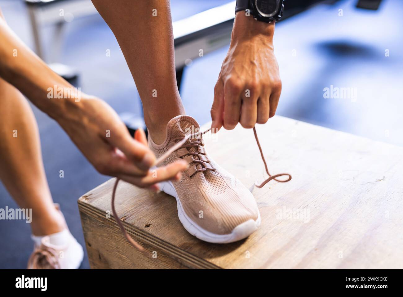 Close-up of a fit person tying their running shoe in a gym setting ...