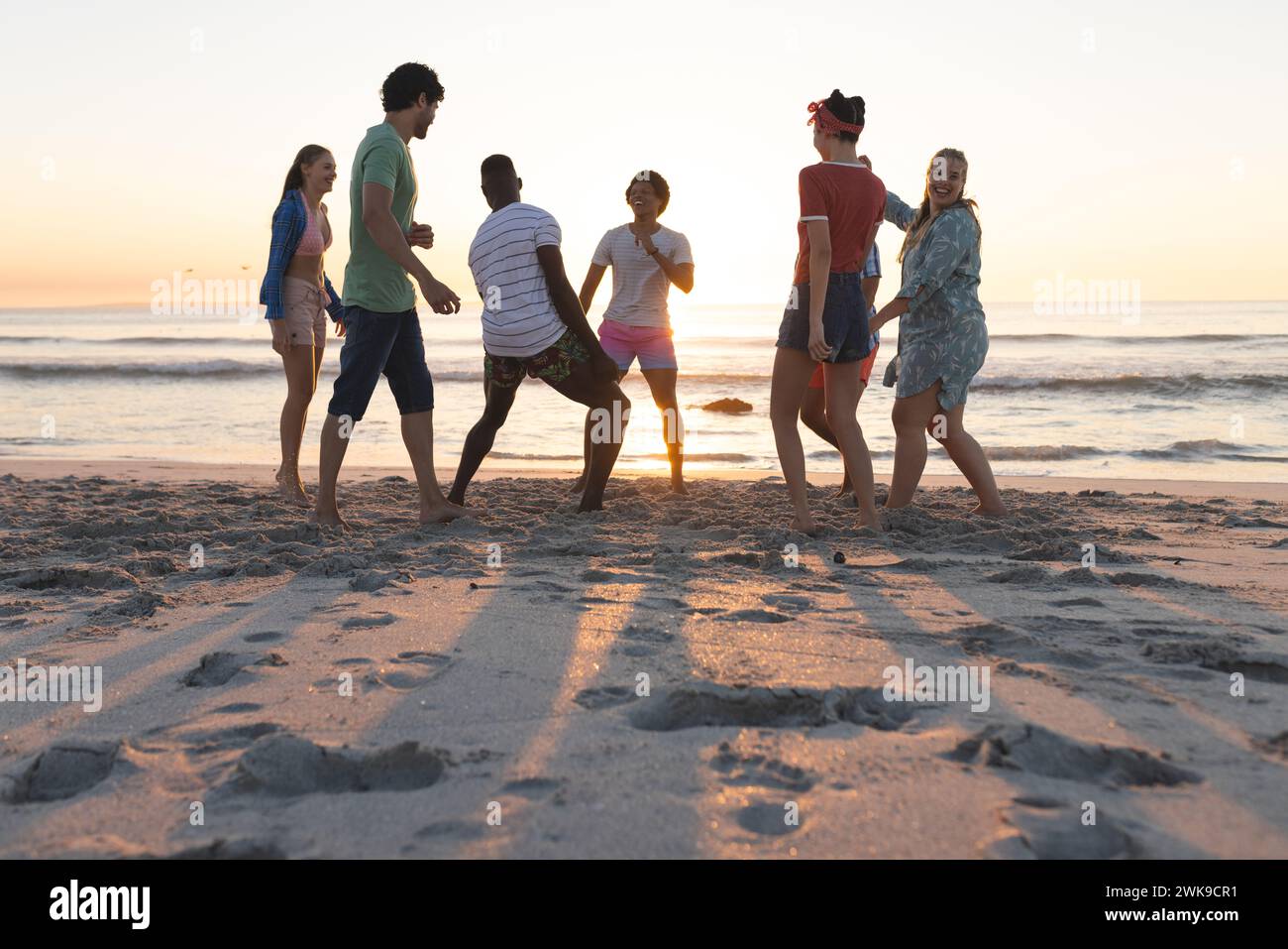 Diverse group of friends enjoy a beach outing at sunset Stock Photo - Alamy