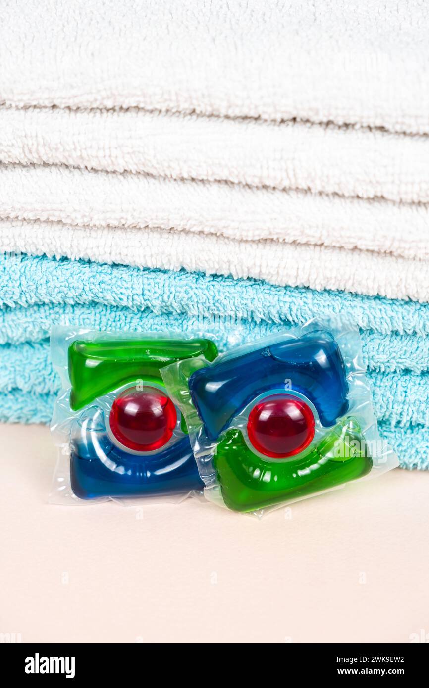 Laundry pods on beige background with soft towels Stock Photo - Alamy